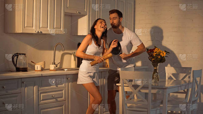 happy man with frying pan dancing near joyful girl