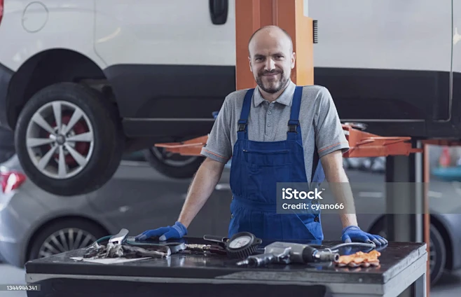 Professional mechanic posing in the auto repair shop Smiling mechanic ...