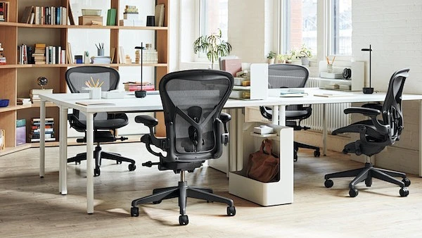 An open-plan office with four desks arranged together two-by-two, each ...