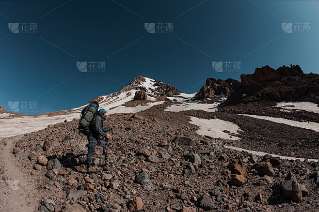 一个人站在崎岖的山路上，仰望着高山