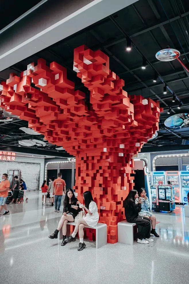 This may contain: people are sitting on benches in front of a large red ...
