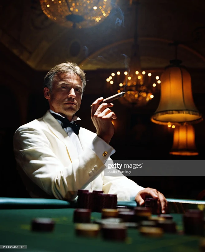 Man wearing dinner jacket smoking cigar in casino, portrait-花瓣网