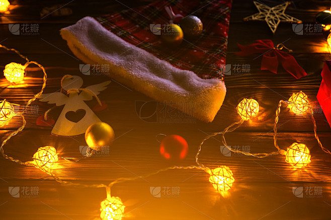 木制桌子上的圣诞装饰品。灯，小装饰品和圣诞老人帽。晚上浪漫的心情。舒适的气氛。假日公寓。节日的概念。