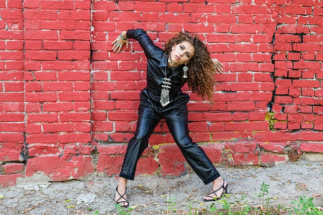 穿着时髦格子衬衫的时尚年轻女模特站在街上砖红粉相间的墙上素材-花瓣网