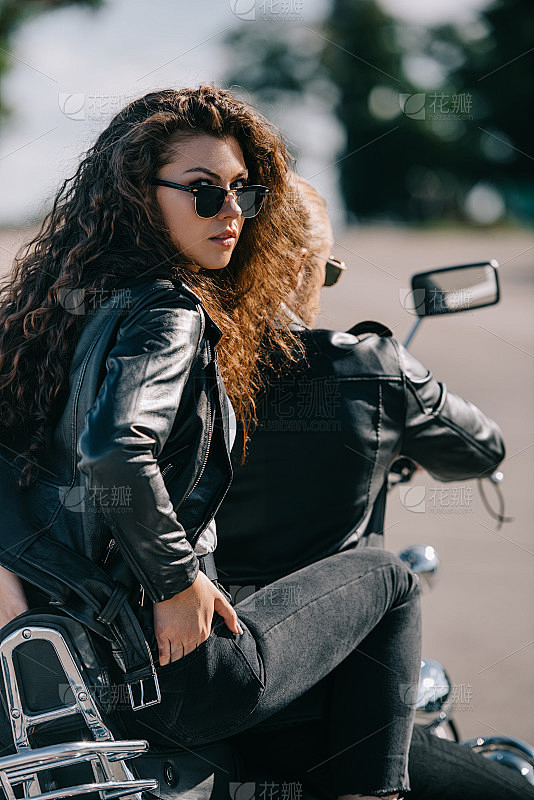 两个骑摩托车的人穿着黑色皮夹克坐在摩托车上