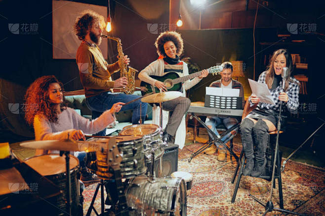 乐队练习在家庭工作室。当乐队其他成员演奏乐器时唱歌的妇女.