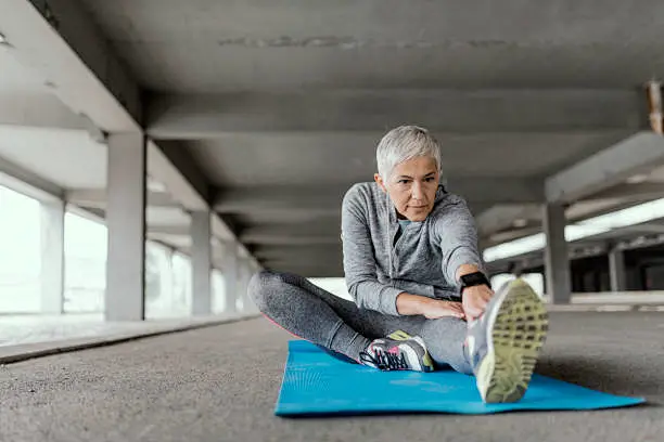 Mature Women stretching legs on Exercise Mat-花瓣网