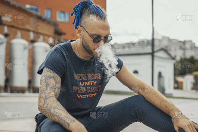 年轻的 vaping 男子与辫子的肖像。蒸气概念。Vaping 电子烟