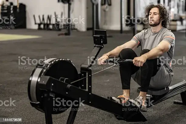 Workout on a Rowing Machine Muscular male using rowing machine in gym ...