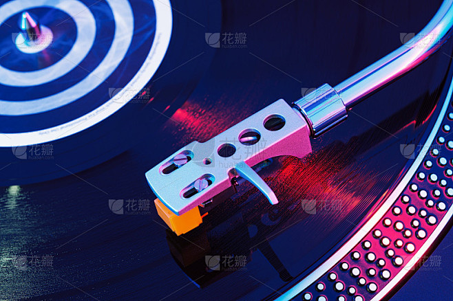 唱片机。音响技术为DJ混合和播放音乐。红黑胶唱片。标签。明亮的红色和蓝色灯光照亮了板块的表面。针与针