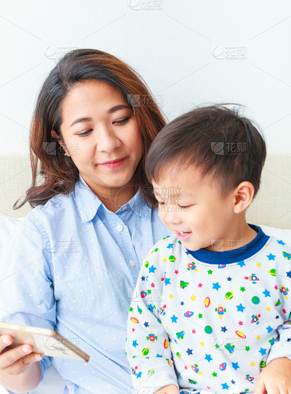 妈妈和宝宝在房间的床上拿着手机。