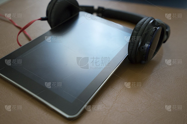 耳机和数码平板电脑放在棕色皮垫上