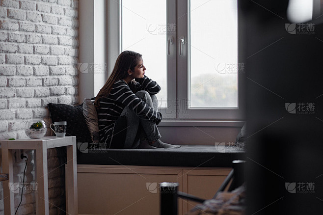年轻女孩坐在窗边喝着咖啡，放松着。
