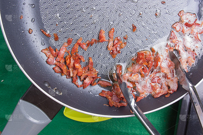 厨师用钳子从锅里取出煎培根