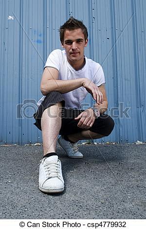 young-man-kneeling-down-with-blue-wall-stock-photo_csp4779932