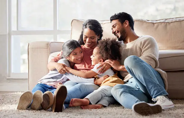 affectionate and loving mixed race family sitting together. happy family with two daughters ...