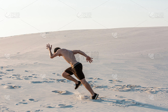 Fit man running fast on the sand. Powerful runner training outdoor on summer