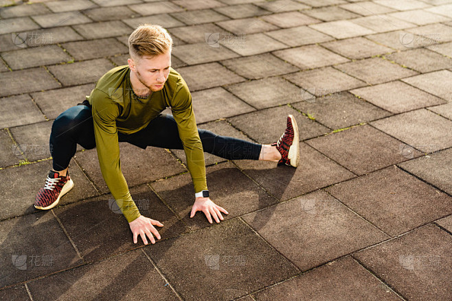 这位强壮的运动员在阳光明媚的天气里在户外伸展身体