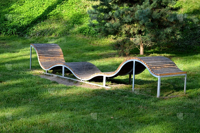 设计一个波浪线形状的长凳。金属镀锌框架上的木质镶板。这张长椅在城市公园里对年轻人来说是不常见的，坐着素材-花瓣网