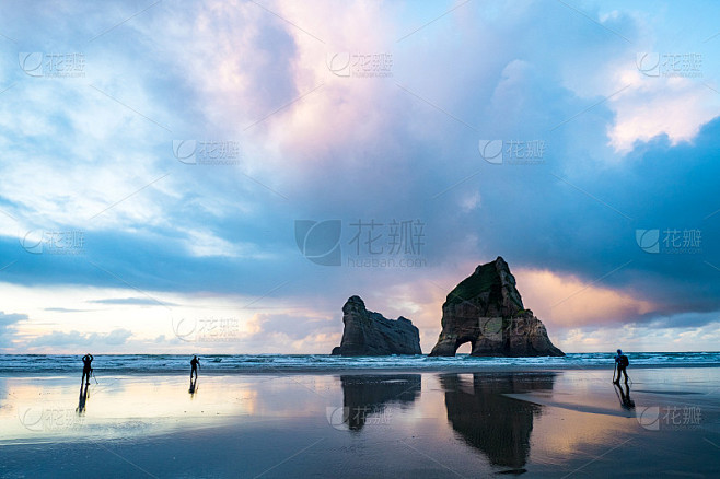 一组摄影师与美丽的瓦拉里基海滩和著名的岩石。夕阳的景象，金色的光和剪影。纳尔逊，南岛，新西兰。