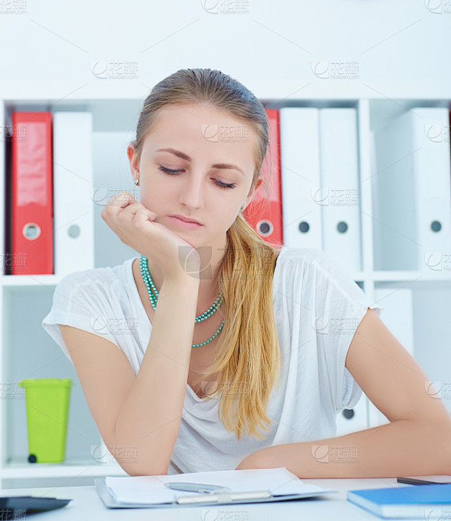无聊的女职员坐在她的办公桌前看文件。