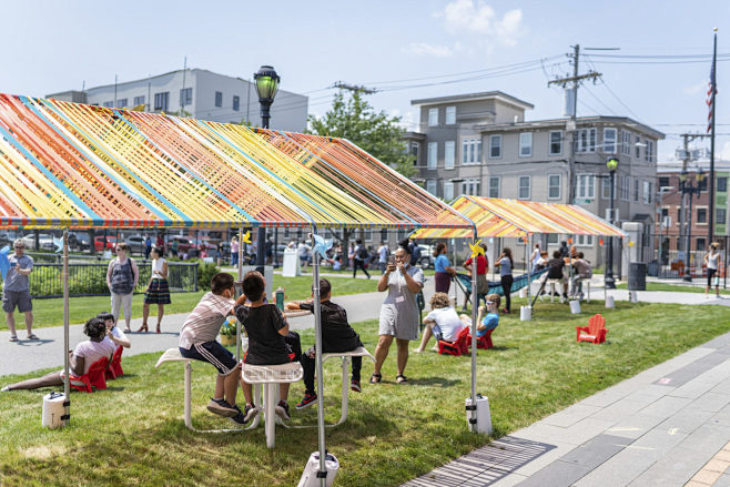 Someone takes a picture of a group of children under a colorful shade ...