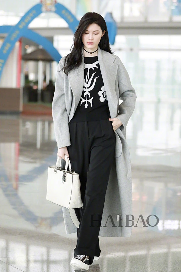 何穗2018年1月21日北京机场街拍：身着Acne Studios灰色束腰大衣，搭配迪奥 (Dior) 2018早春度假系列织花毛衣，踩同品牌同系列运动鞋，拎Dior大号Canyon皮质 ...