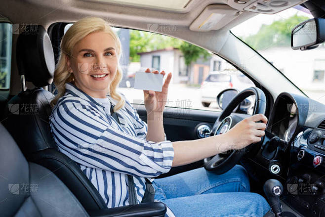 Positive blonde driver holding license in auto