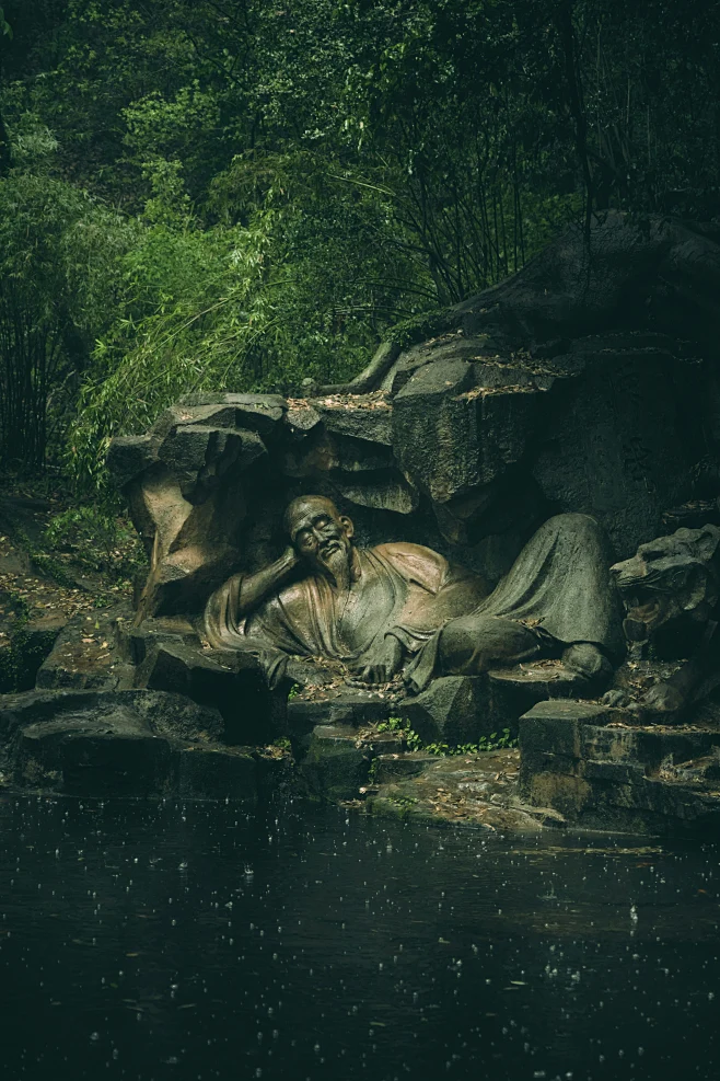 A statue of a relaxed figure in nature.-花瓣网