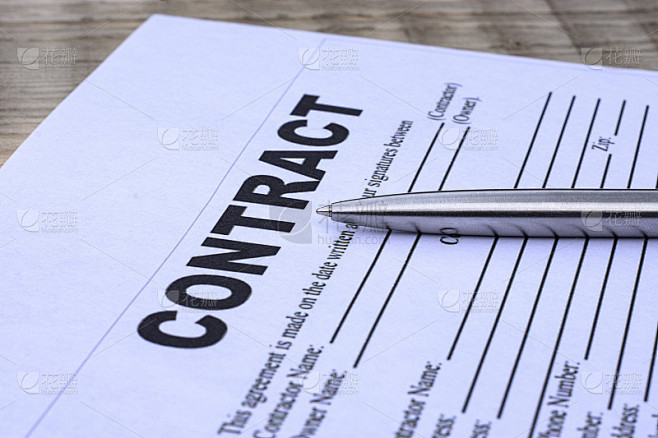 一张写着“contract”和“contract”的纸放在一张木桌上
