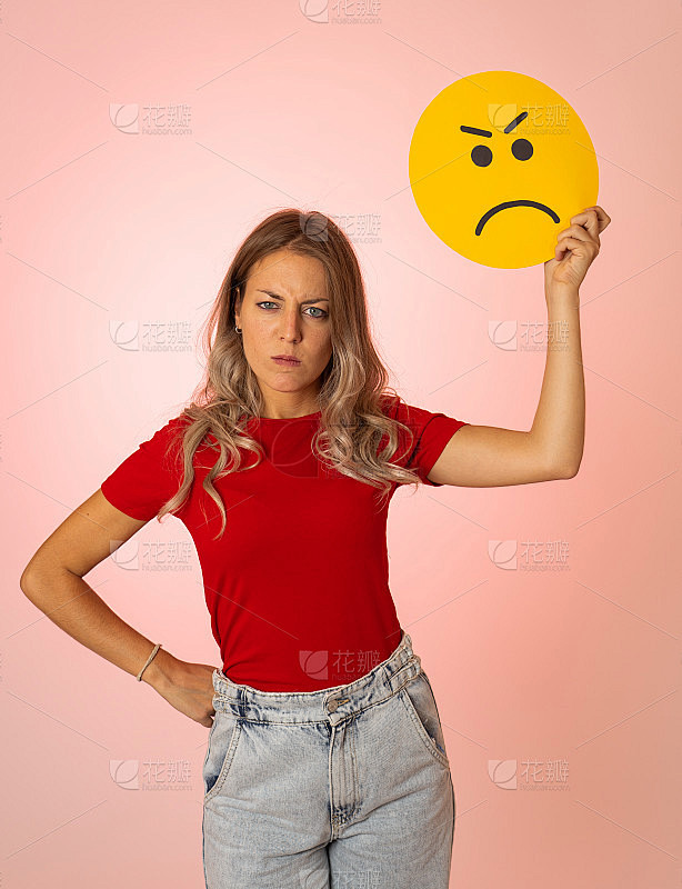Attractive young woman holding an angry face emoji
