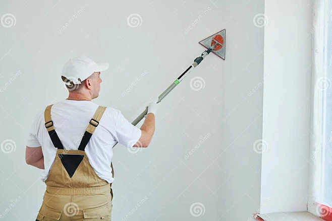 画家工作角度沙磨机 铺沙在油灰以后的墙壁角落表面绘的. 画家与壁角沙磨机一起使用 擦亮和铺沙墙壁内在角落表面在油灰以后 在家绘 ...