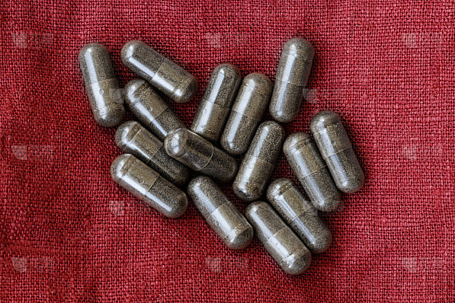 close-up of licorice (DGL) capsules, on a red burl