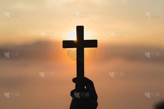 在夕阳的背景下，女人手握基督十字架的圣举。