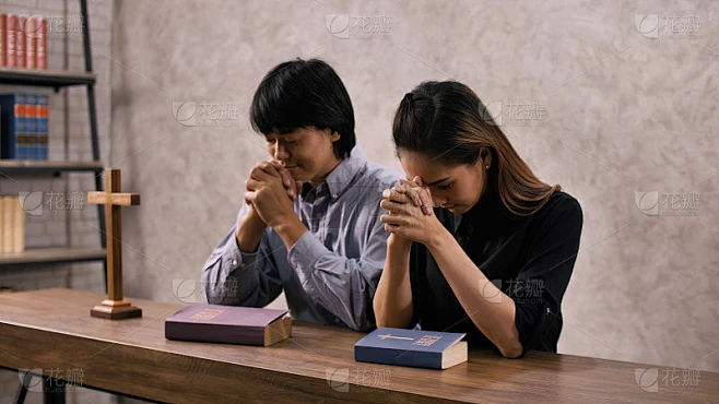 一对年轻的亚洲基督徒夫妇在教堂里向耶稣基督祈祷。素材-花瓣网
