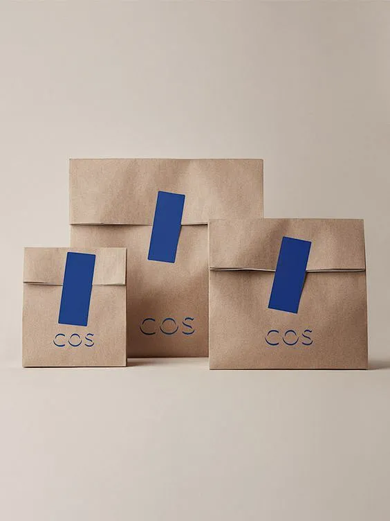This may contain: three brown paper bags with blue stickers on them ...