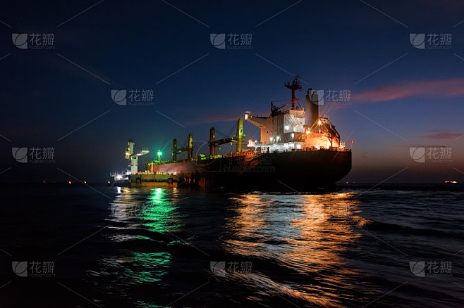 在西非几内亚的Kamsar港口，夜间从小型散货船(支线)船上装载大型母船铝矾土铝矿。