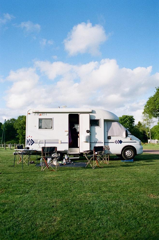 white and brown rv trailer on green grass field under white cloudy sky ...