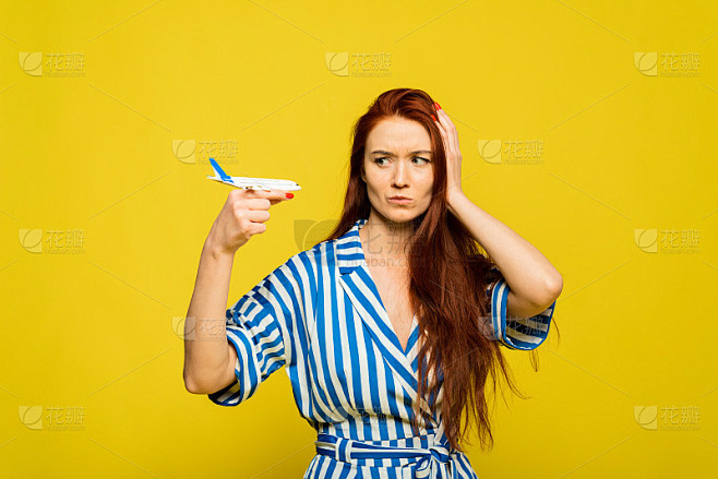年轻美丽的红发女人在黄色背景与愤怒的脸，消极的标志，拒绝概念的飞机。这位女士因丢失行李、度假失败或航