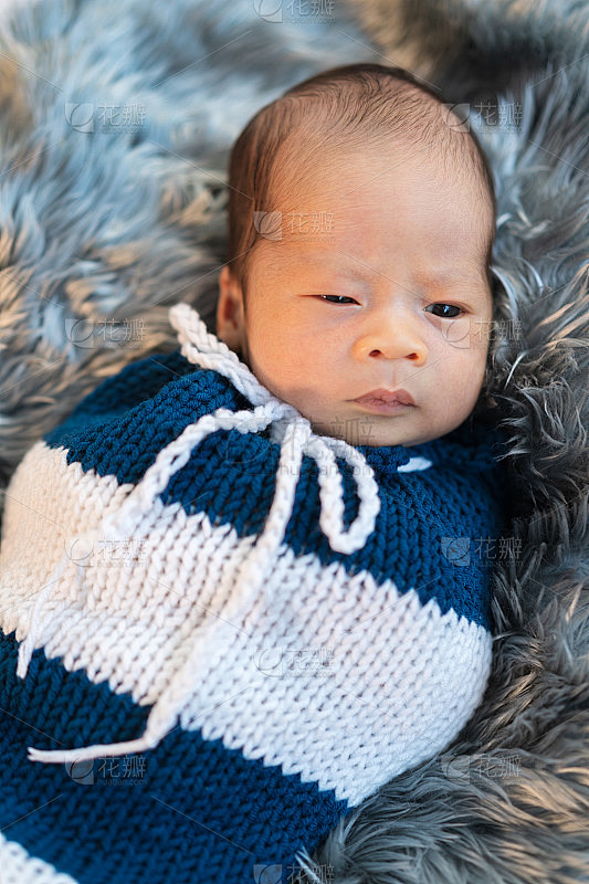 newborn baby boy swaddled in a knit wrap on fur be