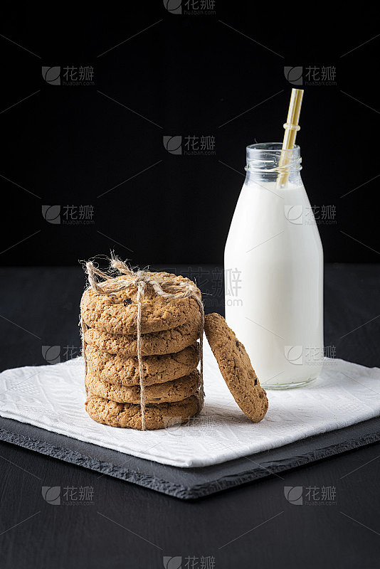 黑色的桌子上放着燕麦饼干和牛奶饮料。