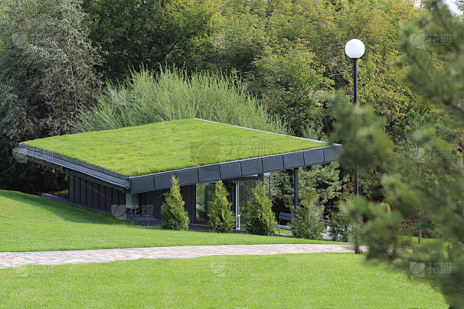 A small modern building in a park with a grassy la