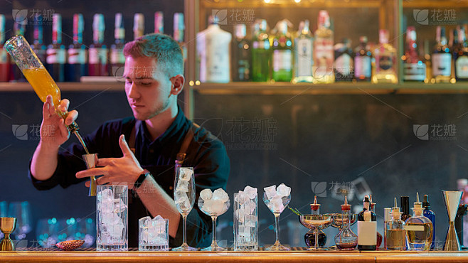 年轻的男调酒师在酒吧柜台上斟酒，调酒，同时制作经典的鸡尾酒酒精饮料