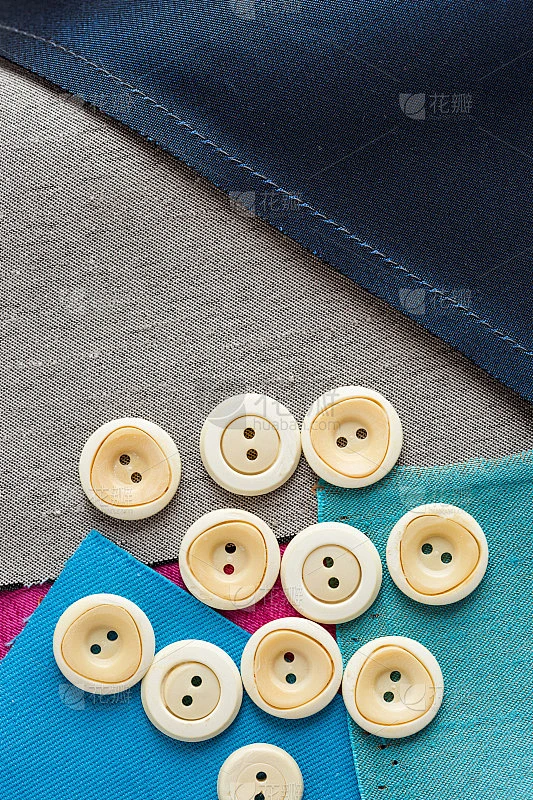 缝纫，拼接，裁剪和时尚概念-特写上的白色纽扣为服装，宏观背景上的蓝色，灰色，紫色的纺织面料，平铺，俯素材-花瓣网