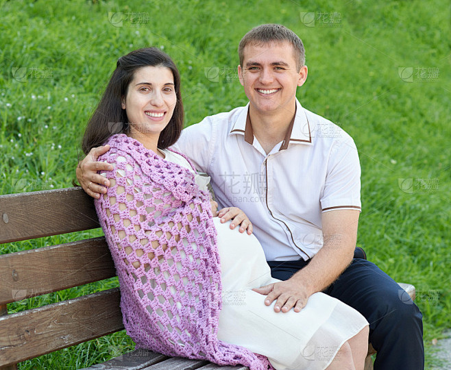 在夏季城市公园的户外，幸福的夫妇，孕妇，阳光明媚的日子和绿色的草，美丽的人画像