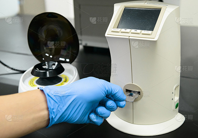 科学家将幻灯片插入实验室的自动细胞计数器，以计算细胞浓度和活力