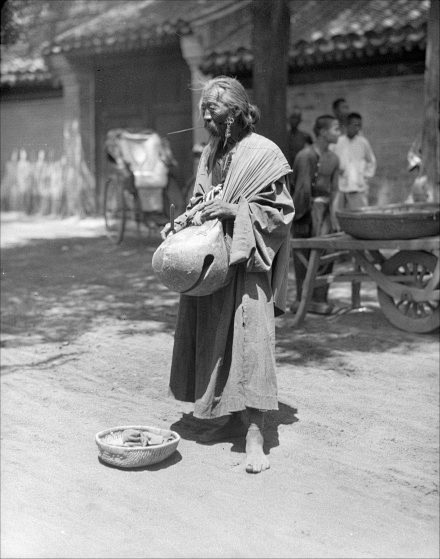 1924-1927年間，北京。一根金屬長籤穿透面頰的老者。他胸前掛著巨大的木魚，還有笸籮和一本小冊子，估計大概是行乞化緣之【乩童】。（西德尼-戴維-甘博 Sidney David Gamble ...